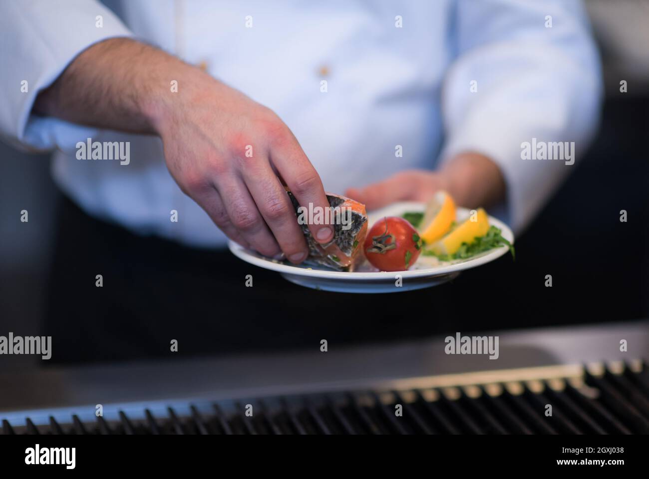 Master chef hands cooking grilled salmon fish with potatoes on a ...
