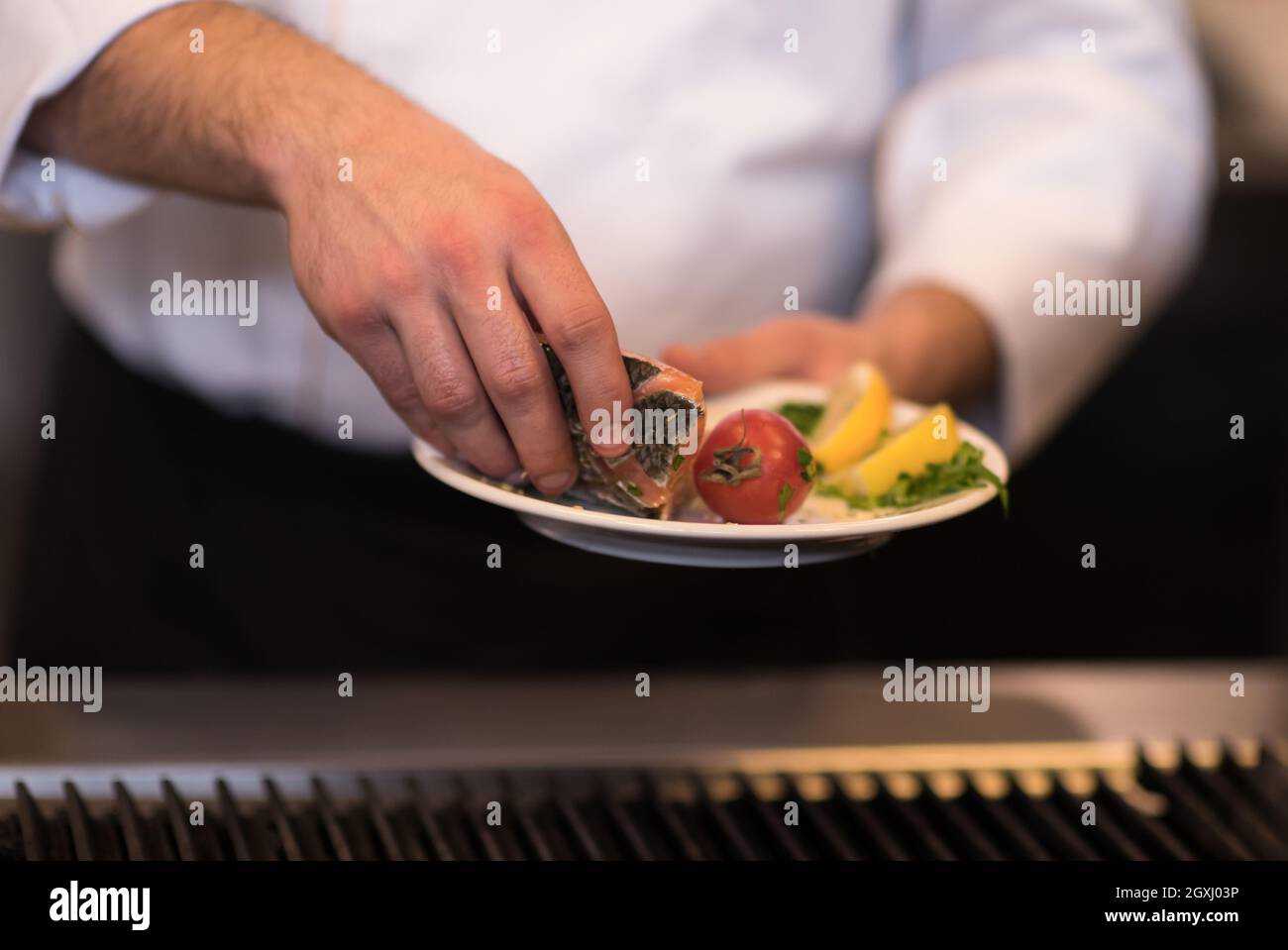 Master chef hands cooking grilled salmon fish with potatoes on a ...