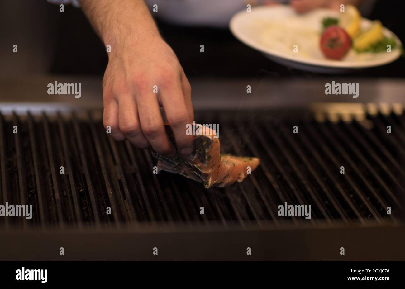 Master chef hands cooking grilled salmon fish with potatoes on a ...