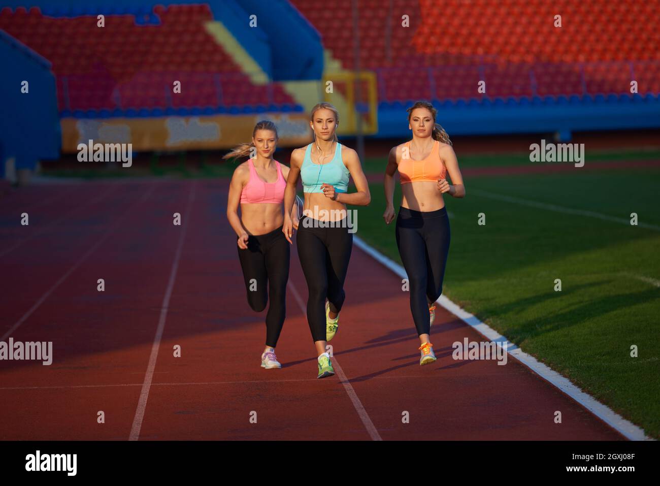 athlete woman group running on athletics race track on soccer stadium ...