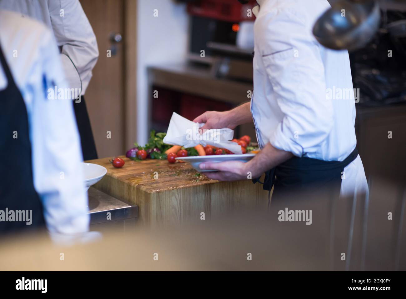 Professional team cooks and chefs preparing meal at busy hotel or ...