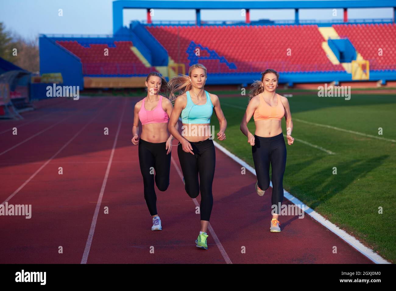 athlete woman group running on athletics race track on soccer stadium ...
