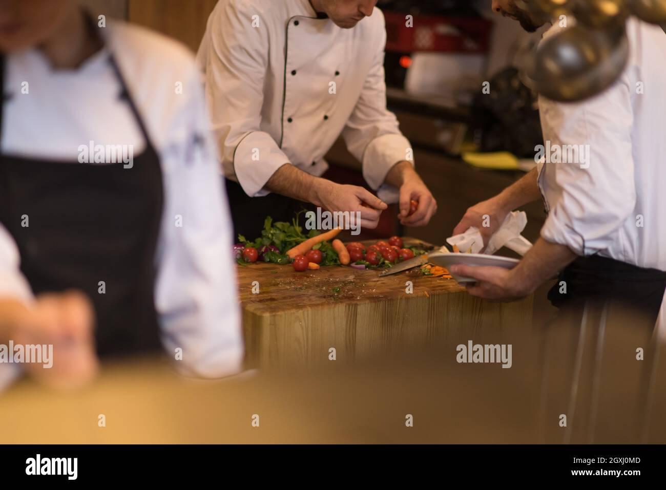 Professional team cooks and chefs preparing meal at busy hotel or ...
