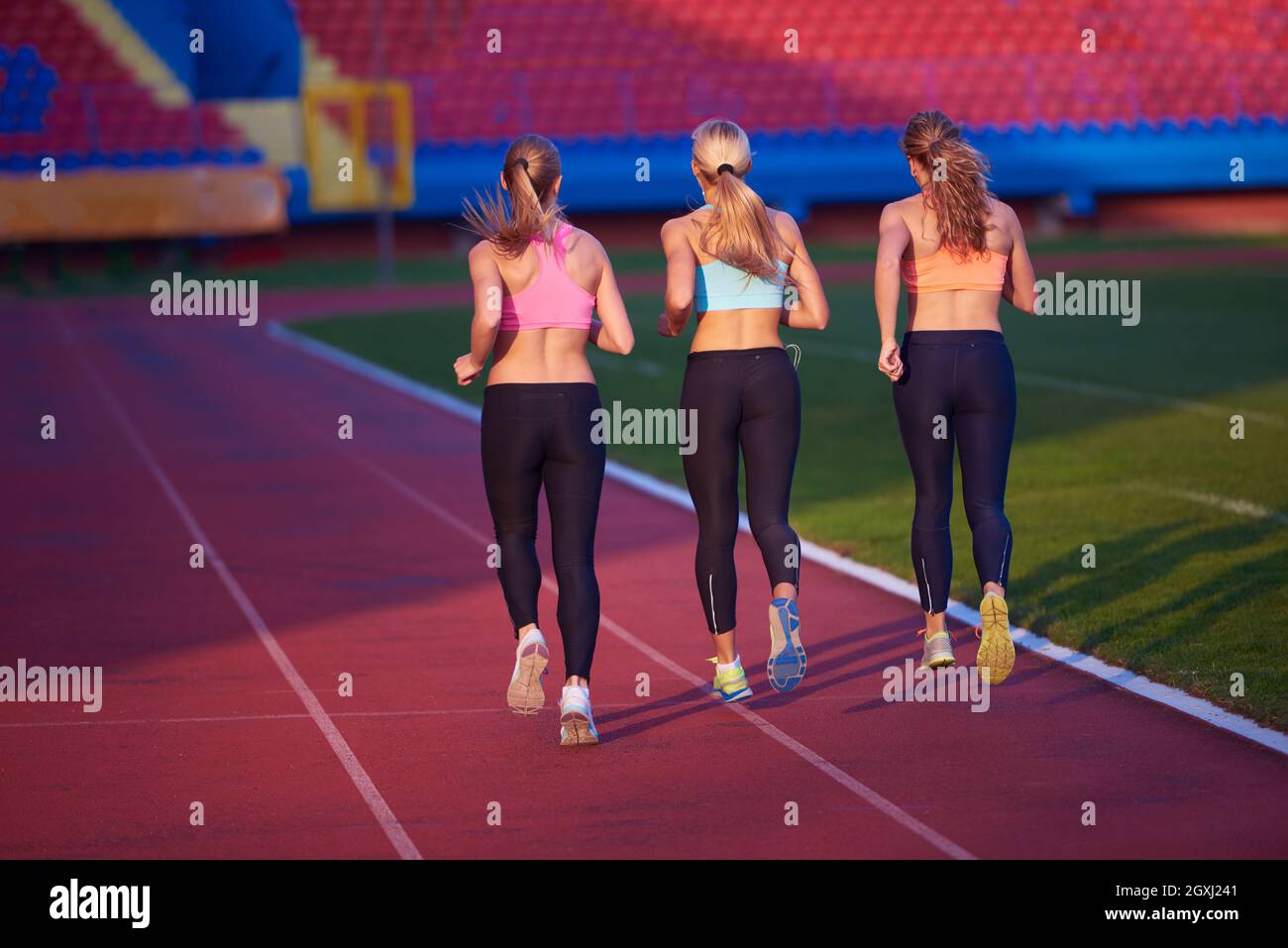 athlete woman group running on athletics race track on soccer stadium ...