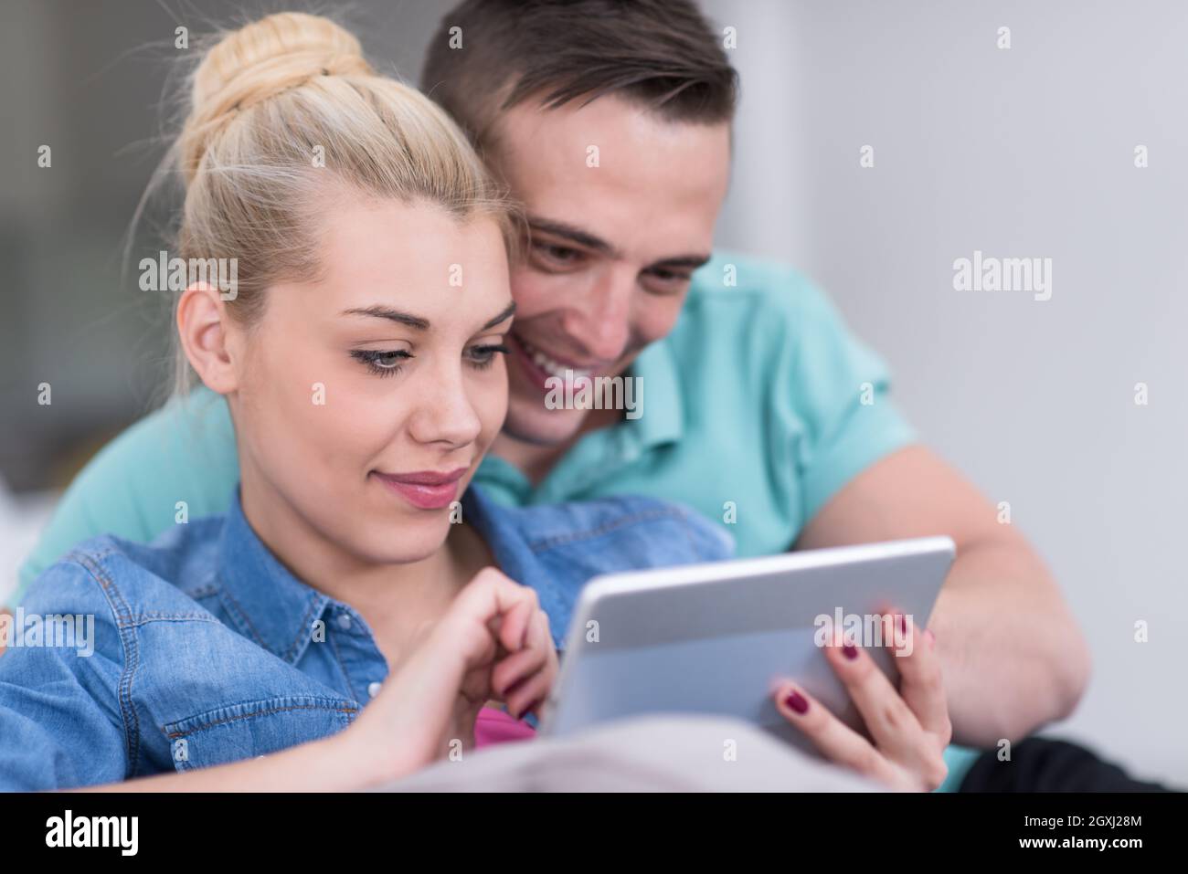Young couple relaxing at luxurious home with tablet computers reading ...