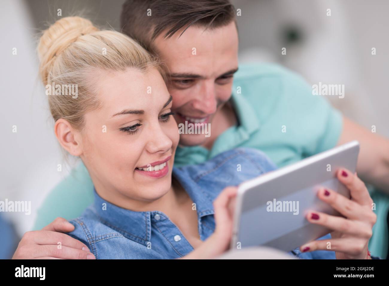 Young couple relaxing at luxurious home with tablet computers reading ...