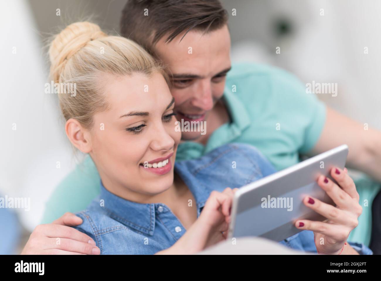 Young couple relaxing at luxurious home with tablet computers reading ...