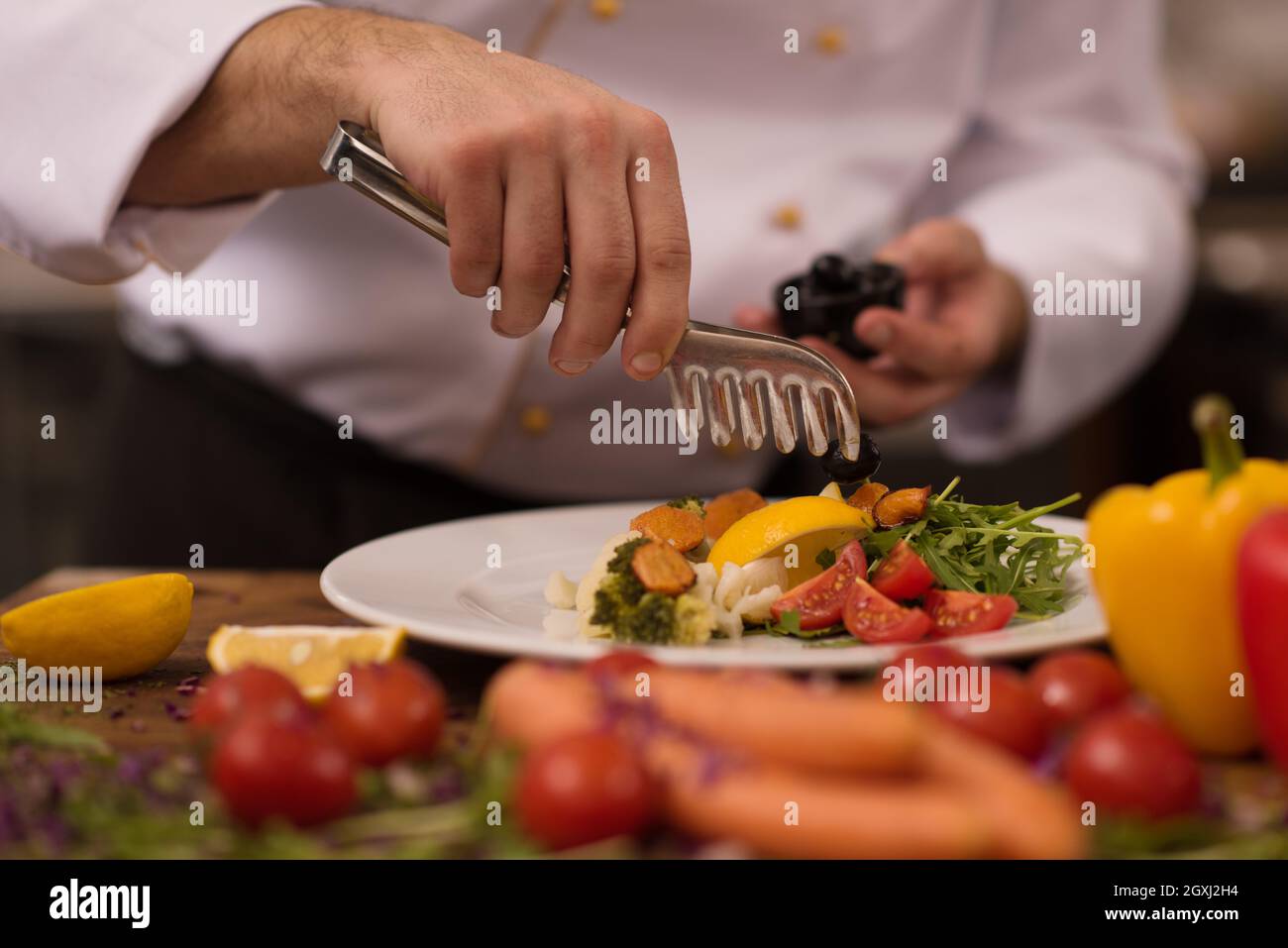 chef serving vegetable salad on plate in restaurant kitchen Stock Photo ...