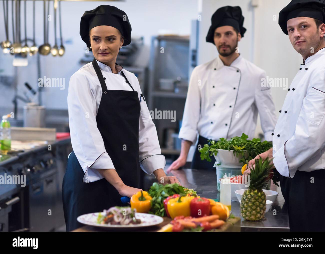 Professional team cooks and chefs preparing meals at busy hotel or ...