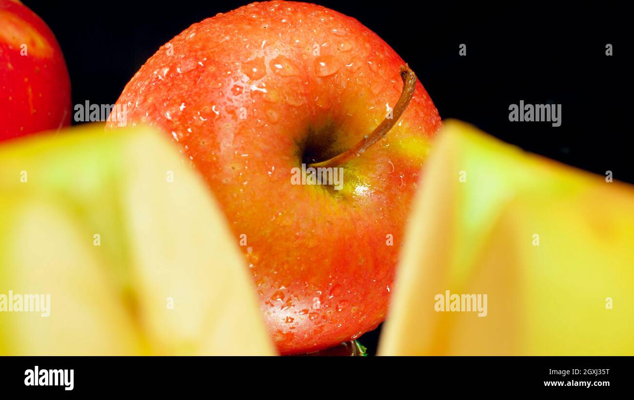 Closeup image of whole red apple and apple pieces against black ...