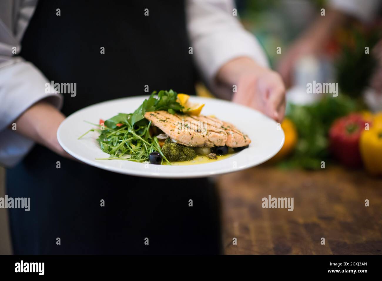 Chef hands holding fried Salmon fish fillet with vegetables for dinner ...