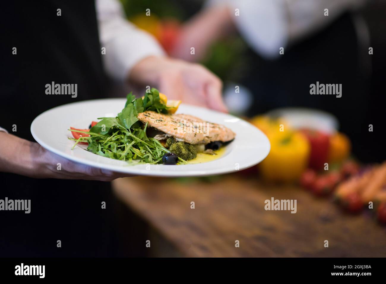 Chef hands holding fried Salmon fish fillet with vegetables for dinner ...
