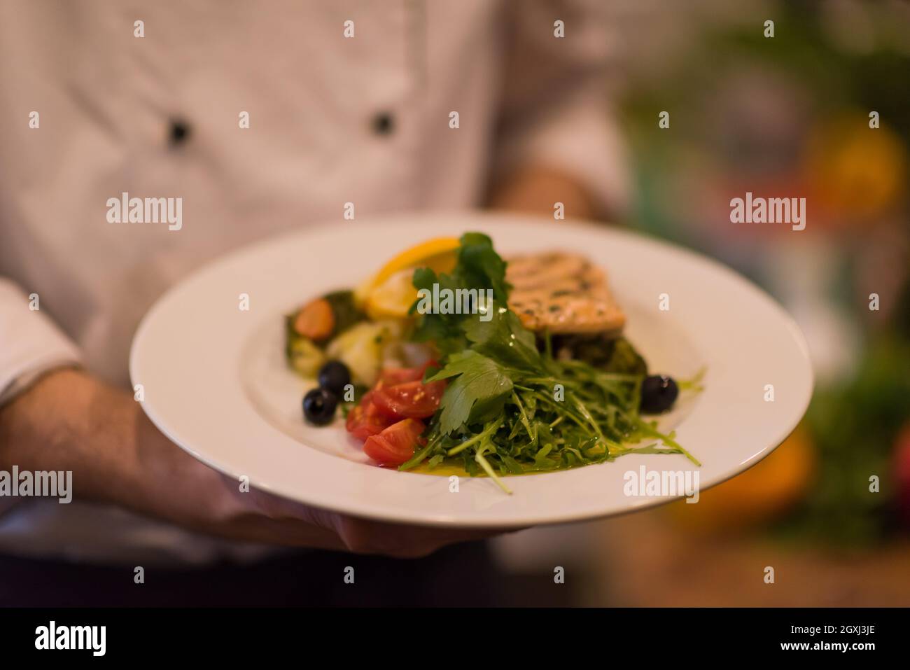 Chef hands holding fried Salmon fish fillet with vegetables for dinner ...
