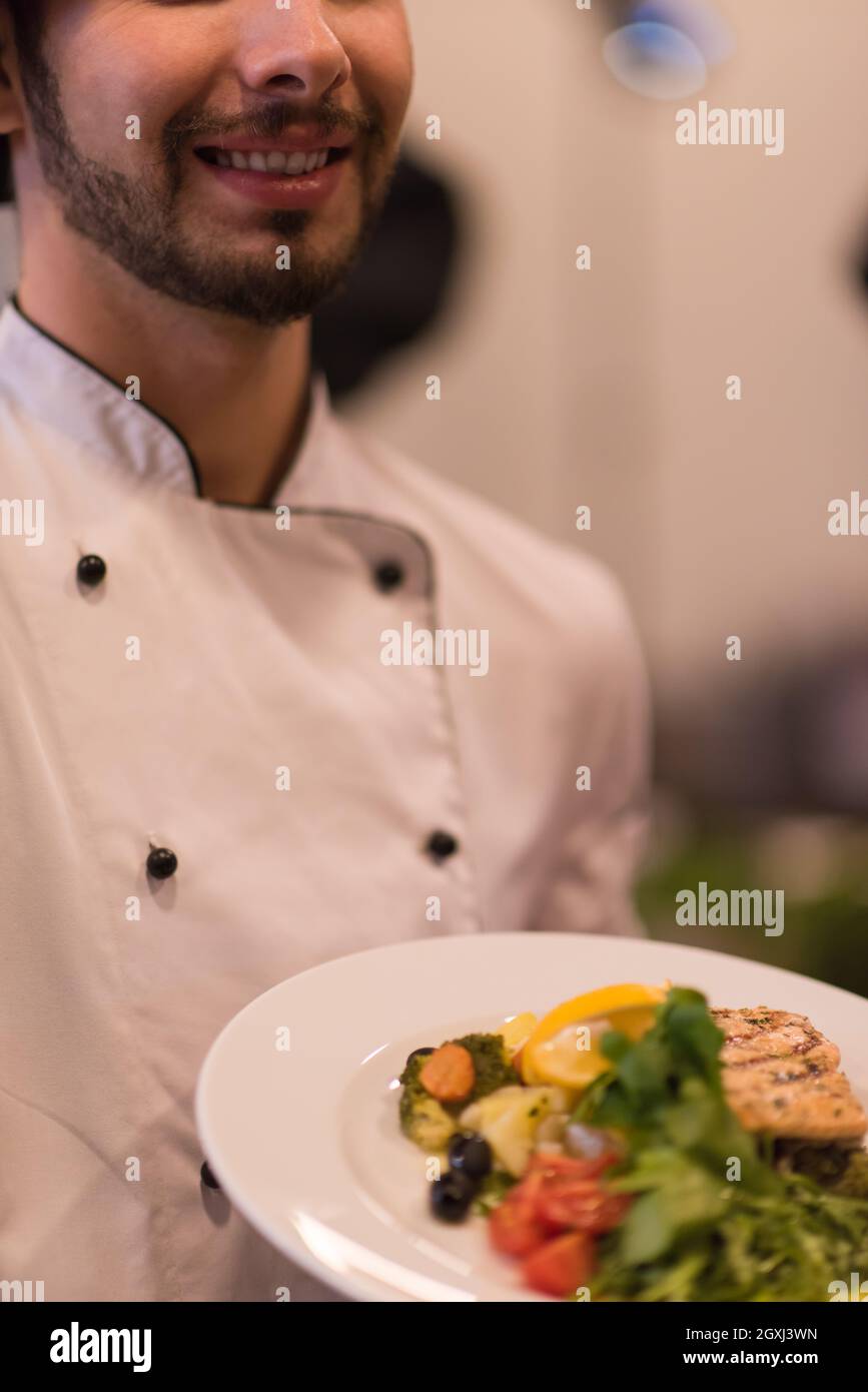 Chef hands holding fried Salmon fish fillet with vegetables for dinner ...