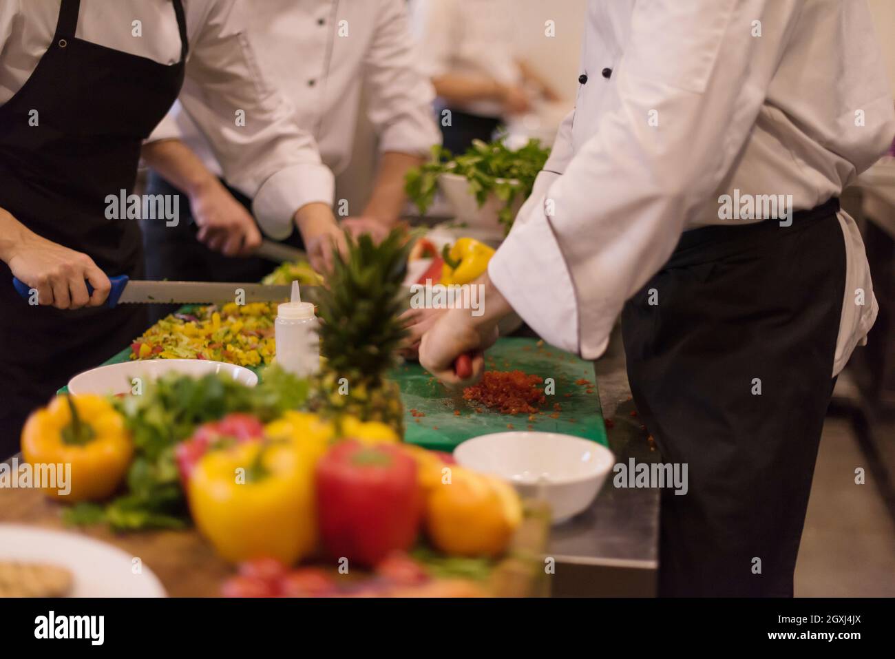 Professional team cooks and chefs preparing meal at busy hotel or ...