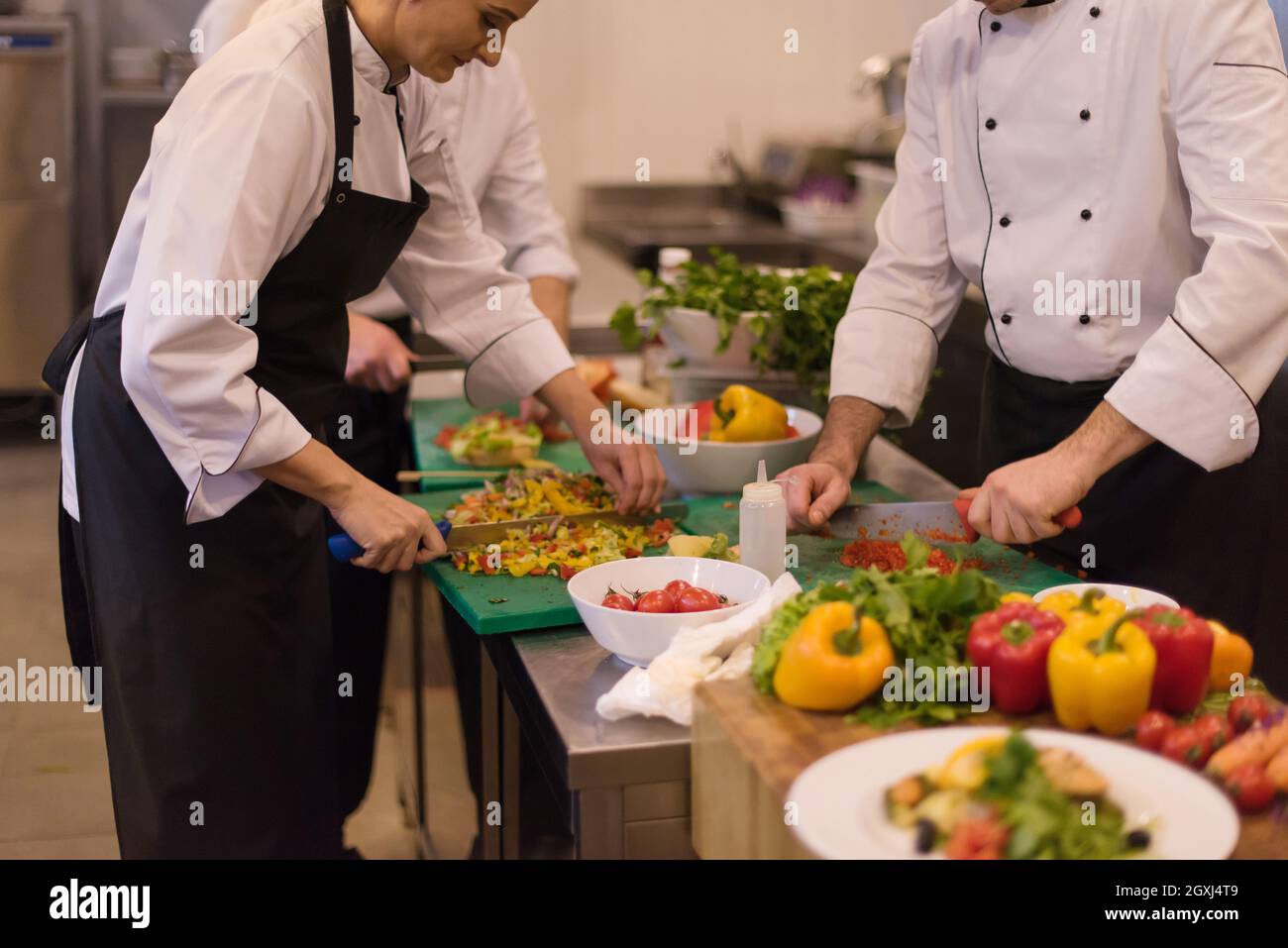 Professional team cooks and chefs preparing meal at busy hotel or ...