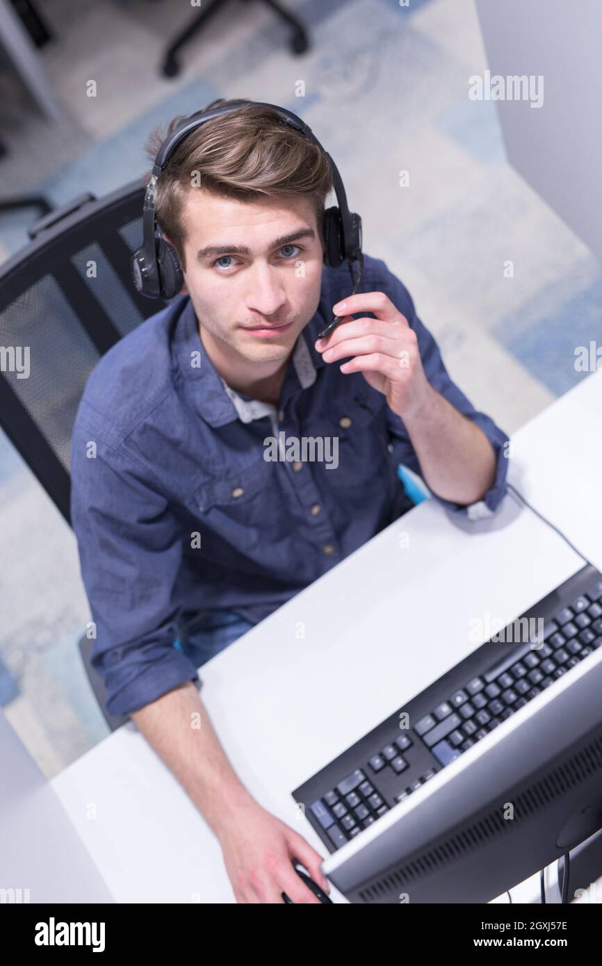 top view of a young smiling male call centre operator doing his job ...
