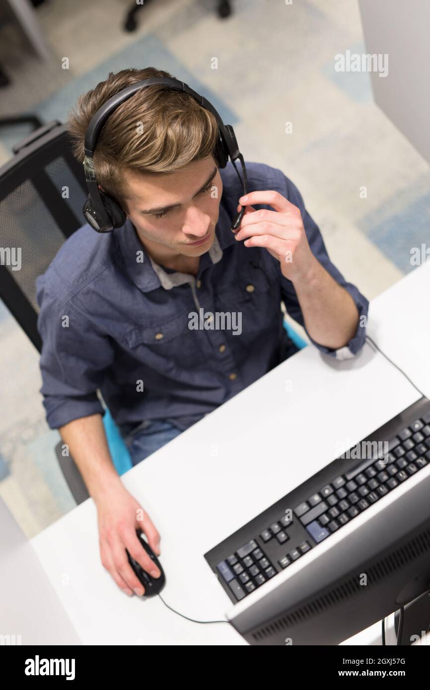 top view of a young smiling male call centre operator doing his job ...