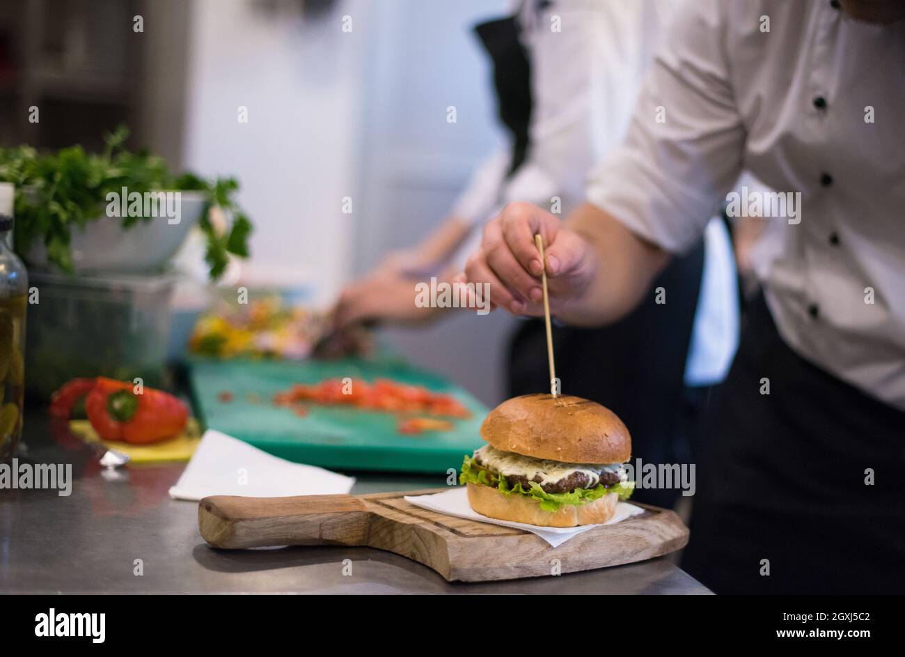 master chef putting toothpick on a burger in restaurant kitchen Stock ...