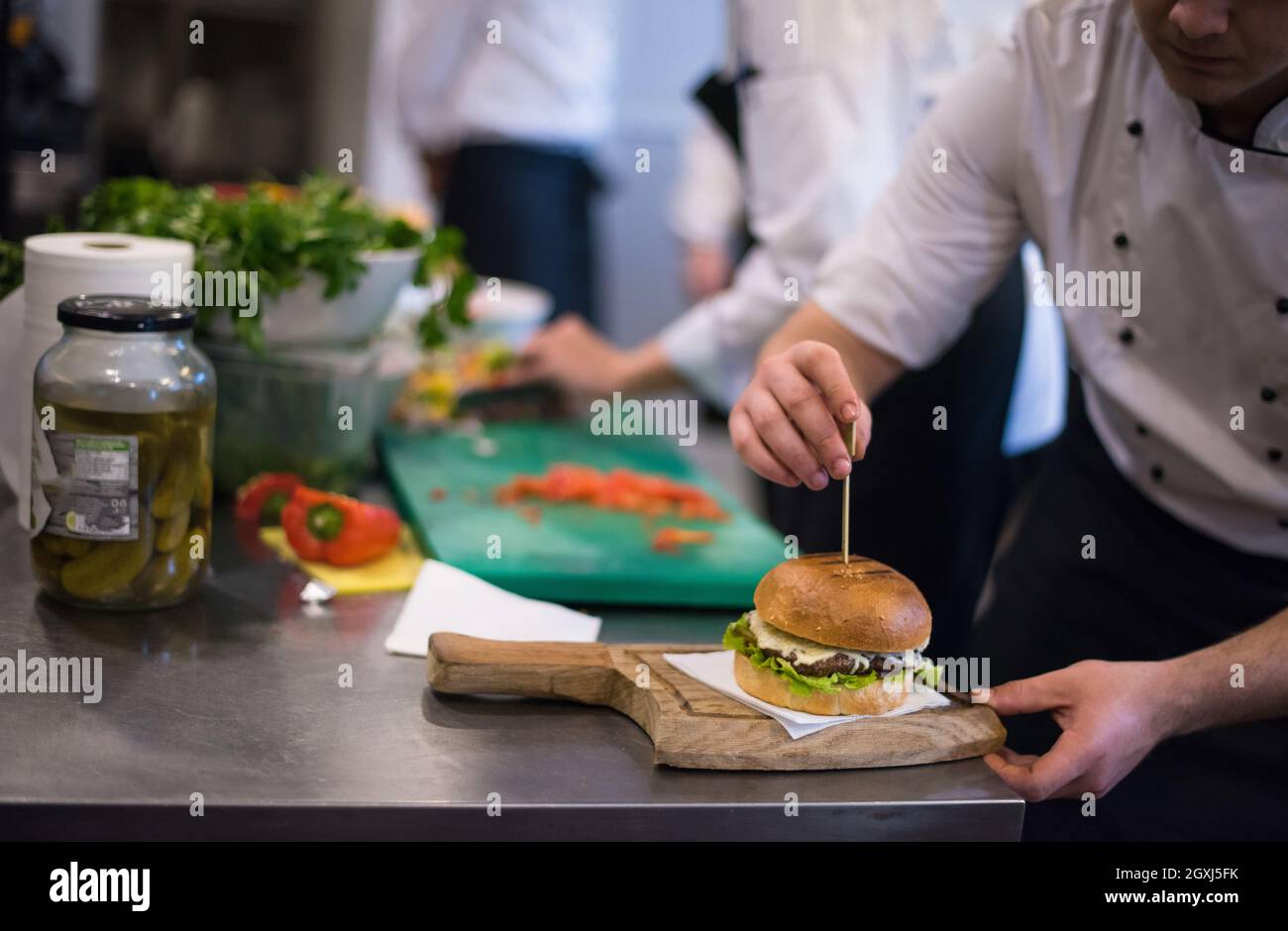 master chef putting toothpick on a burger in restaurant kitchen Stock ...