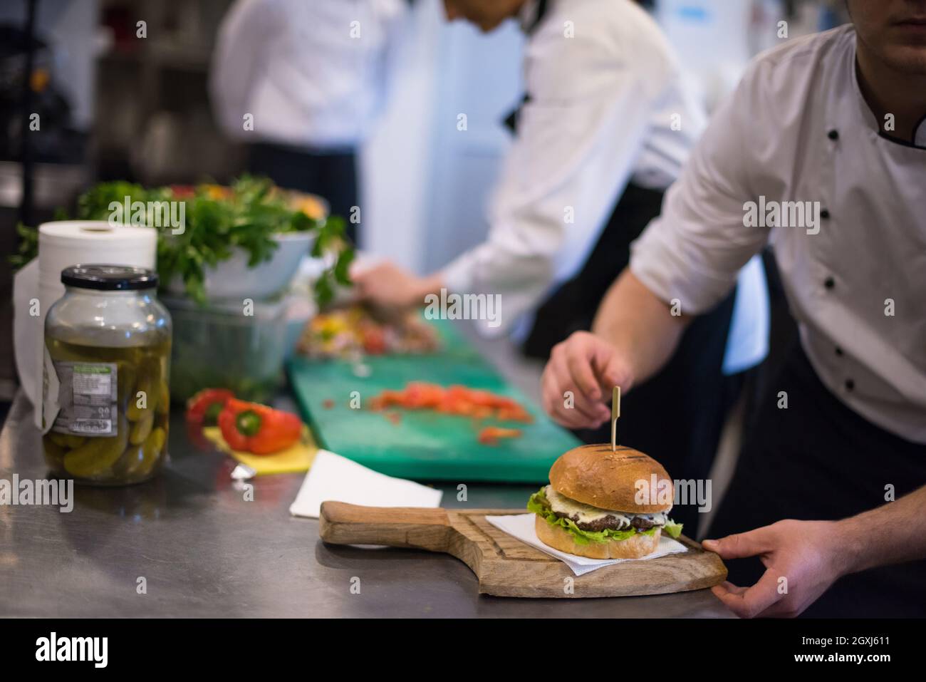 master chef putting toothpick on a burger in restaurant kitchen Stock ...
