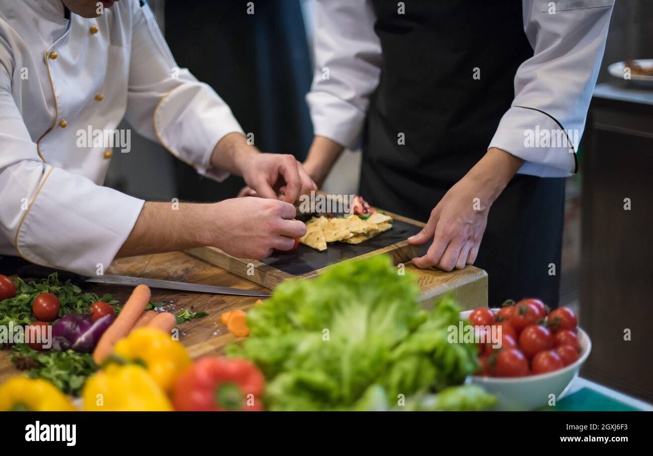 Professional team cooks and chefs preparing meal at busy hotel or ...