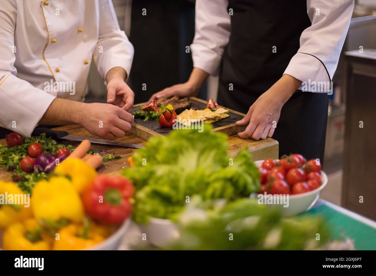 Professional team cooks and chefs preparing meal at busy hotel or ...