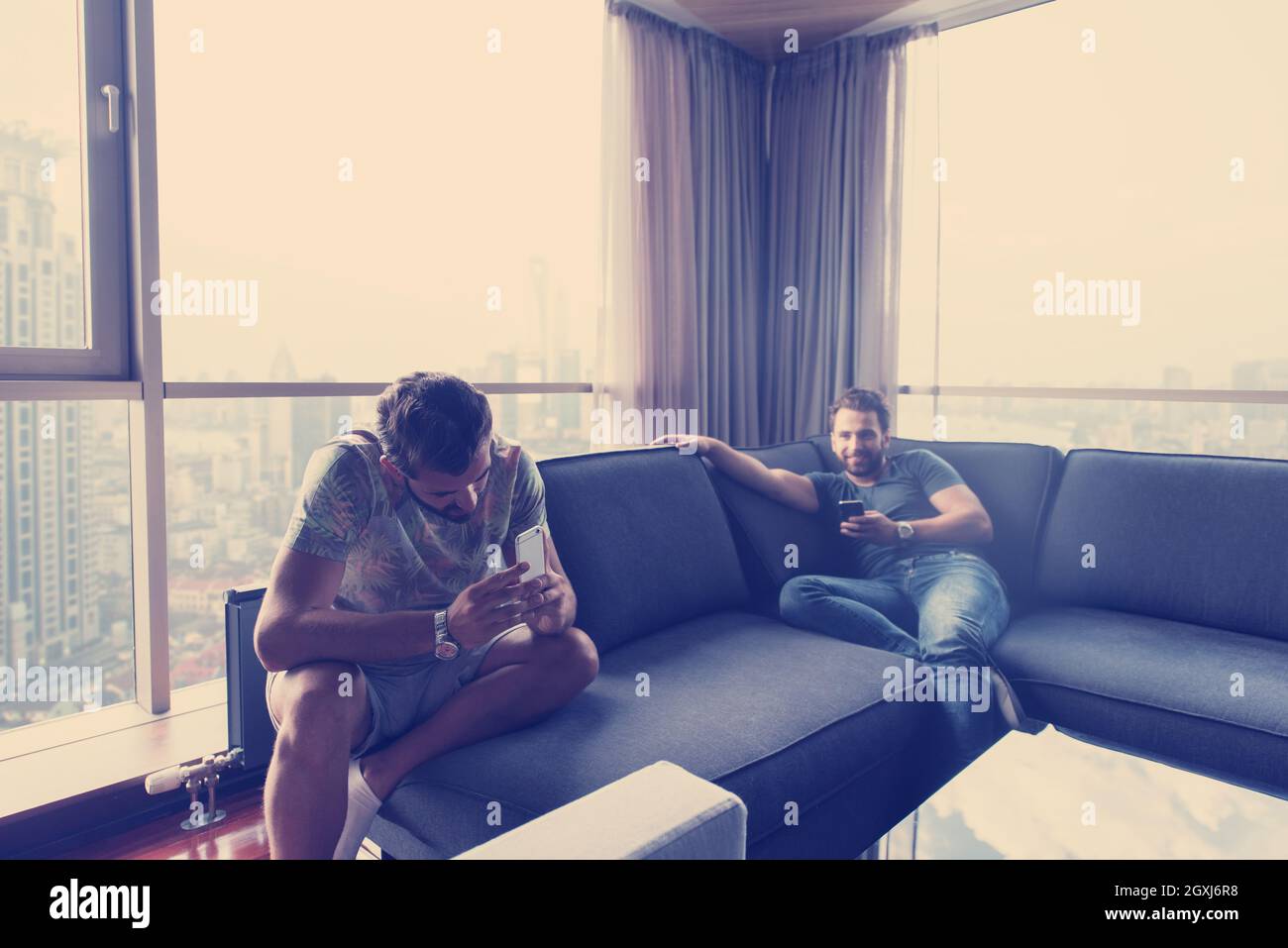 Handsome casual young men using a mobile phones near the window at home ...