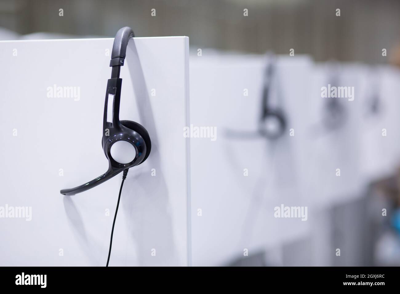 Headphones hanging on cubicle partition in empty call center office ...