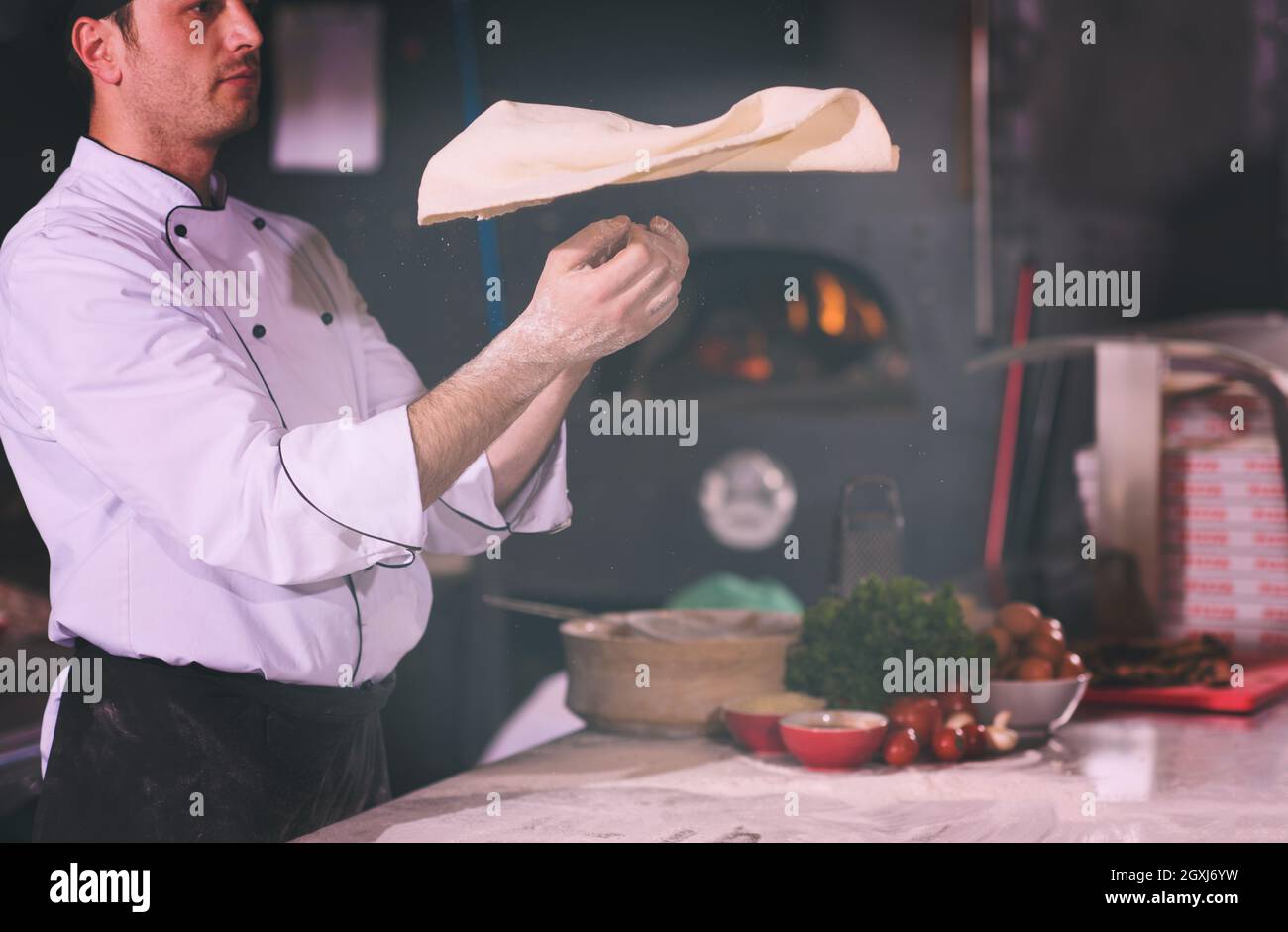 Skilled chef preparing dough for pizza rolling with hands and throwing ...