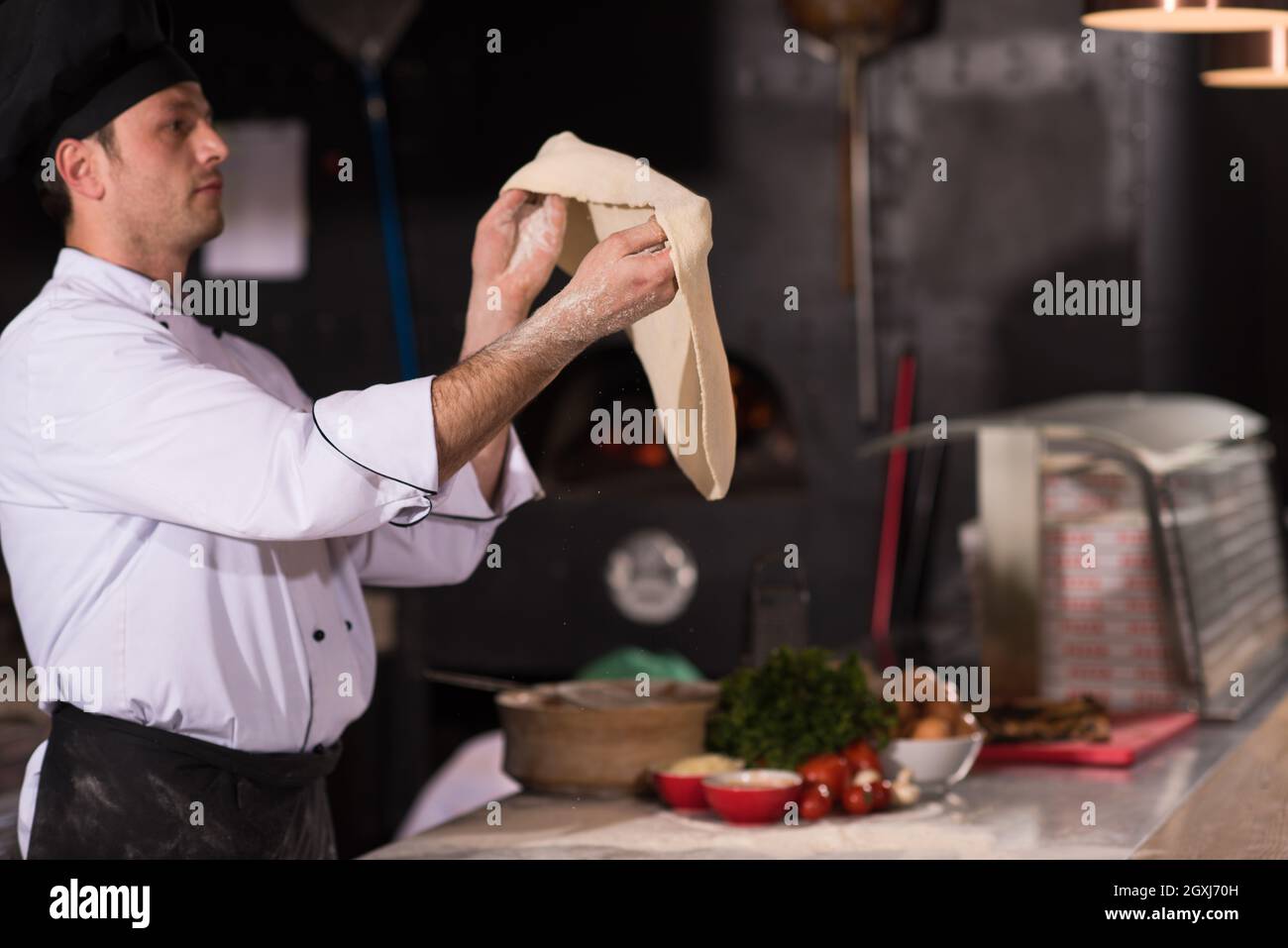 Skilled chef preparing dough for pizza rolling with hands and throwing ...