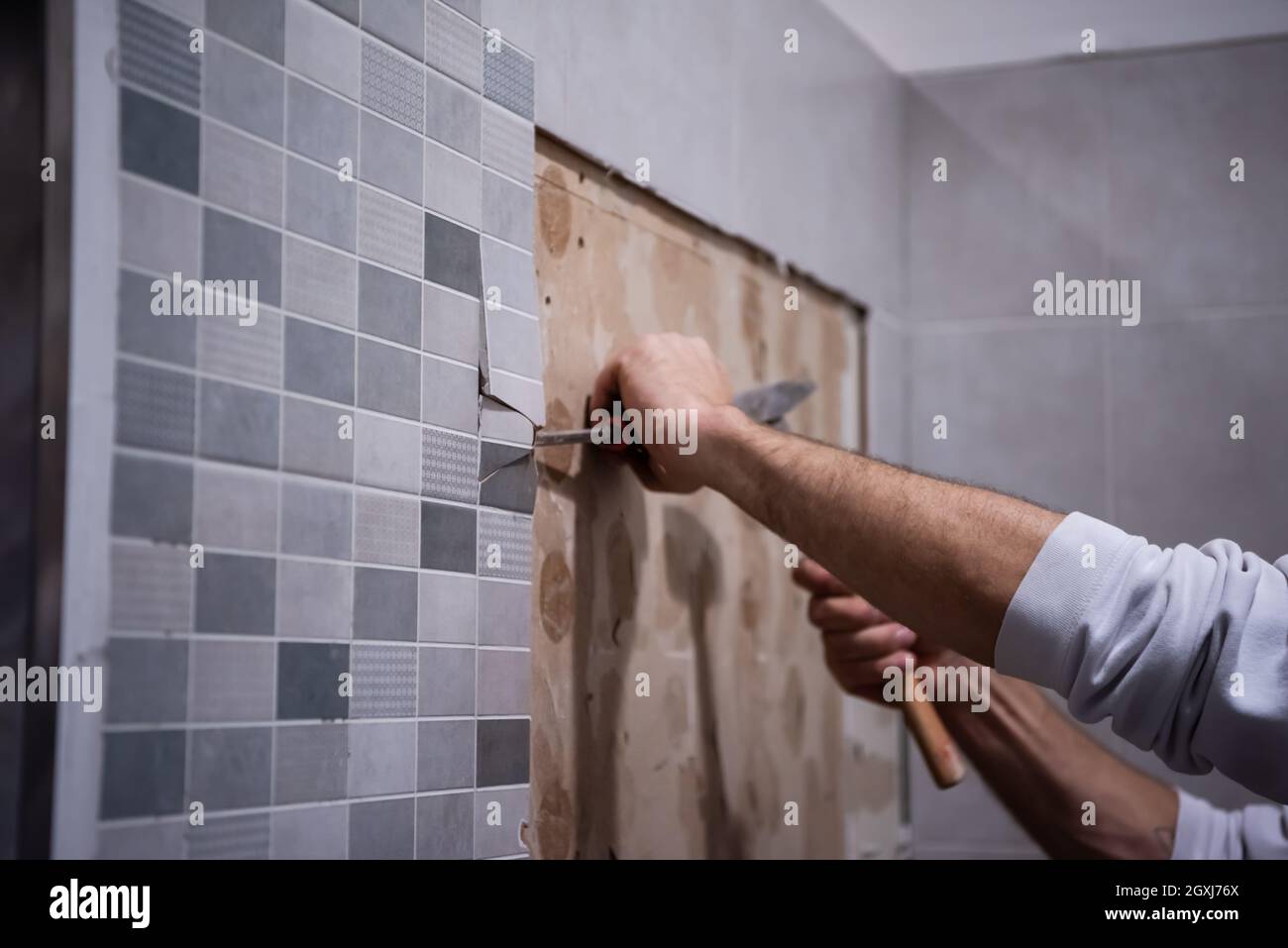 professional worker remove demolish old tiles in a bathroom with hammer ...