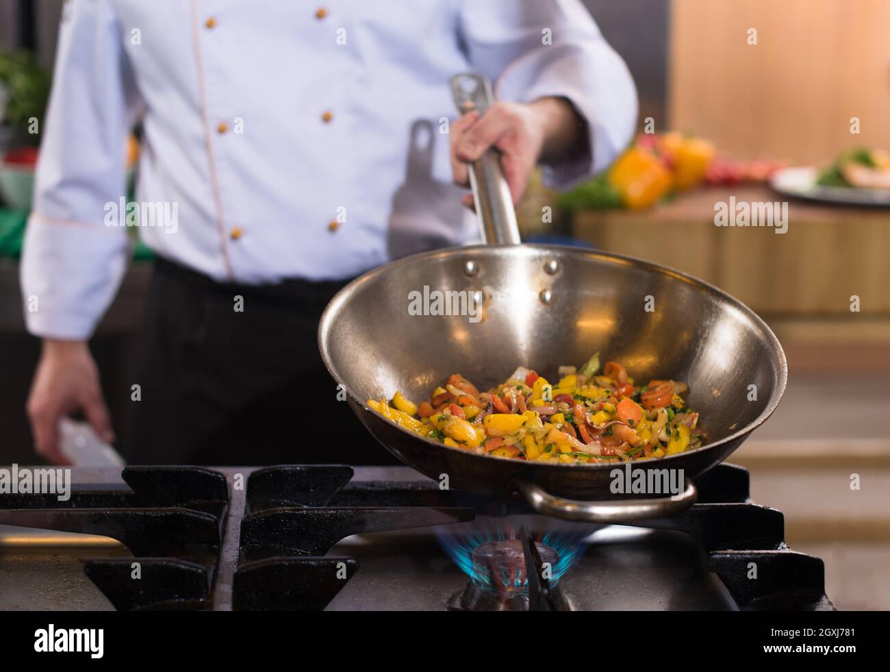 Young male chef flipping vegetables in wok at commercial kitchen Stock ...