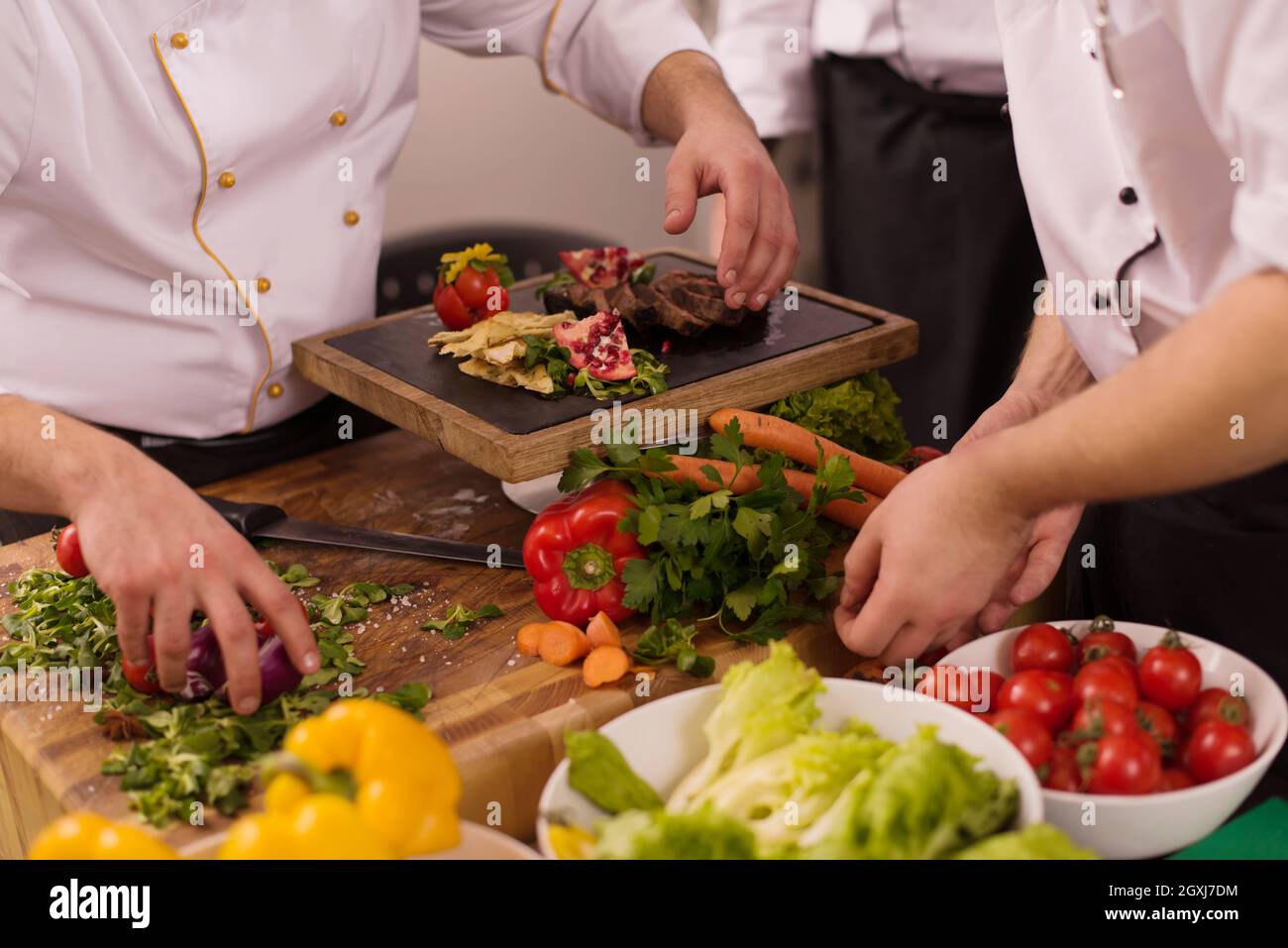 Professional team cooks and chefs preparing meal at busy hotel or ...