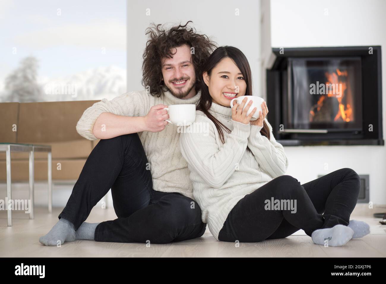 Young romantic multiethnic couple sitting on the floor in front of ...