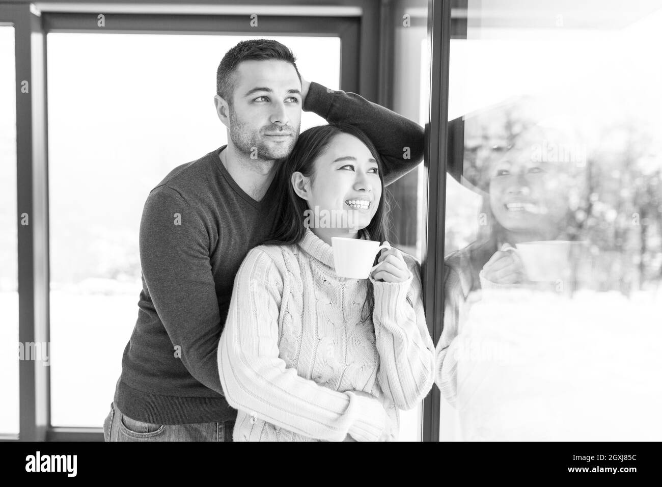 happy young multiethnic couple enjoying morning coffee by the window on ...