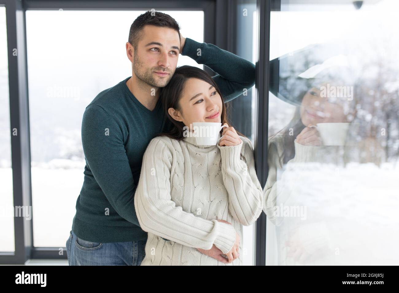 happy young multiethnic couple enjoying morning coffee by the window on ...