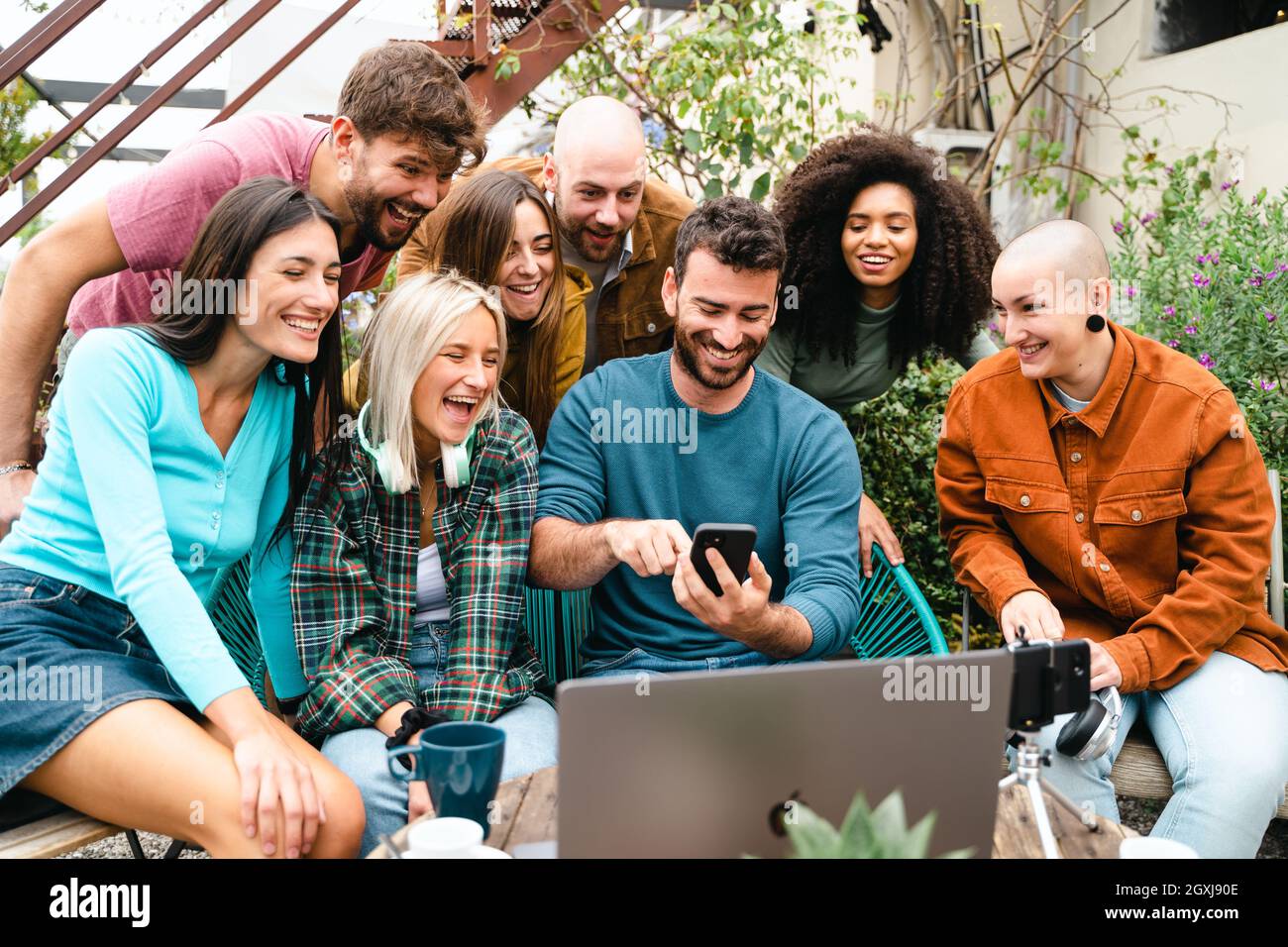 Young students in front a laptop watching content from smartphone while ...