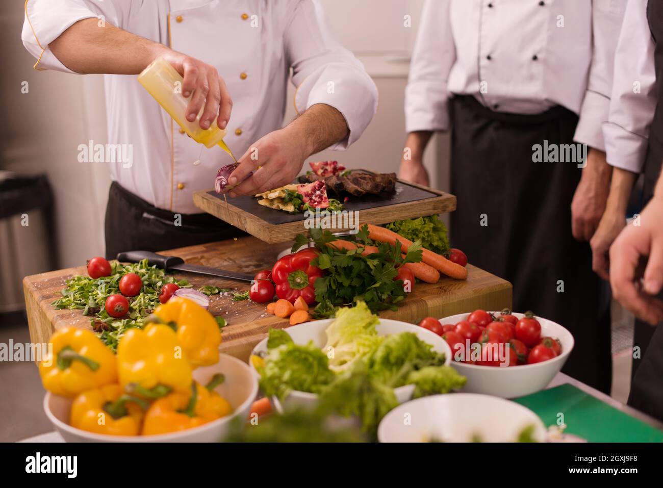 Professional team cooks and chefs preparing meal at busy hotel or ...