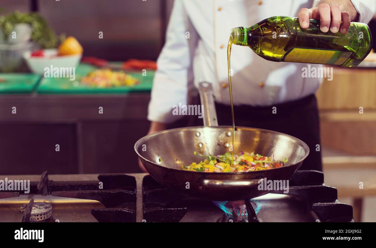 Young male chef flipping vegetables in wok at commercial kitchen Stock ...