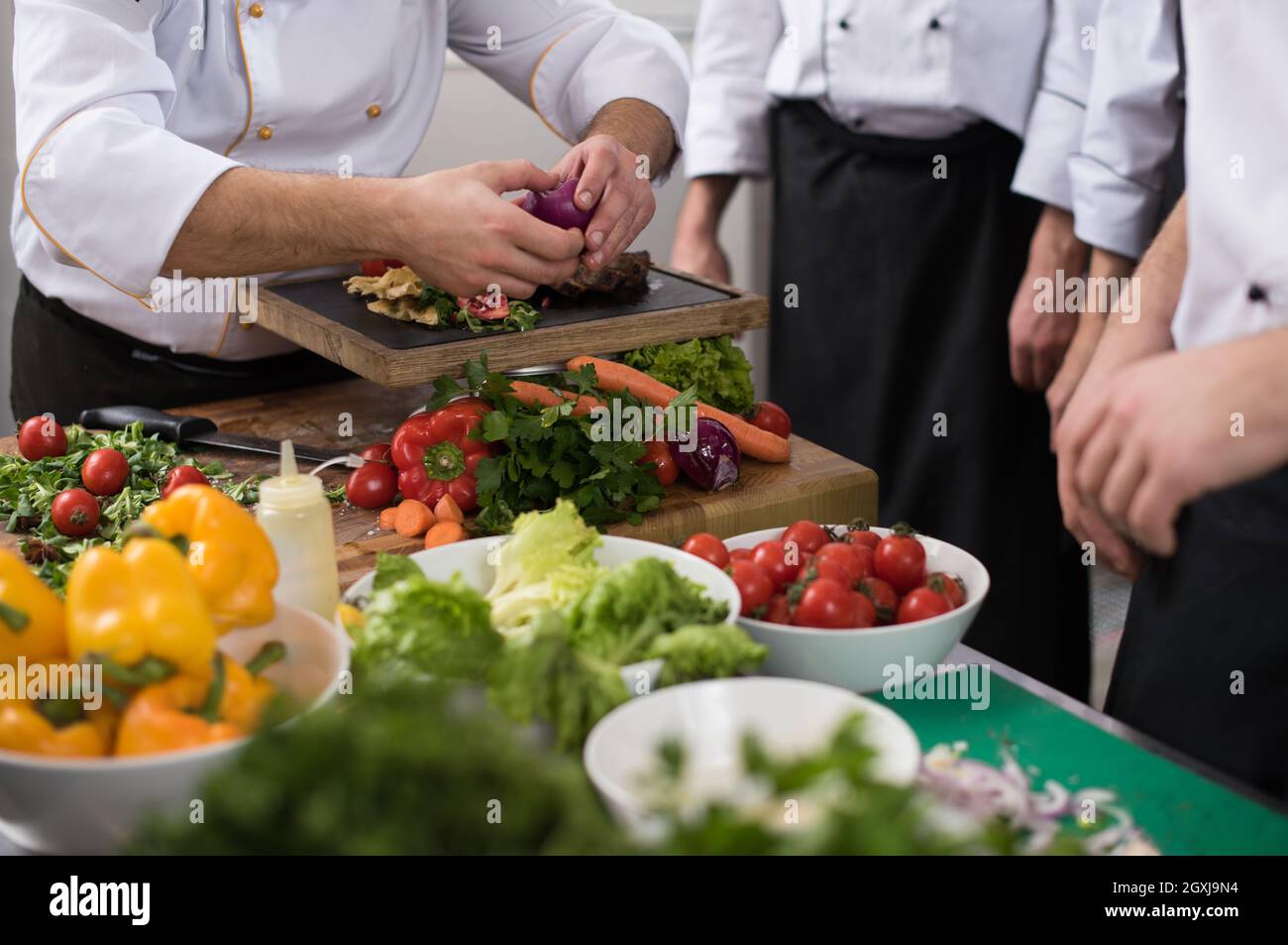 Professional team cooks and chefs preparing meal at busy hotel or ...