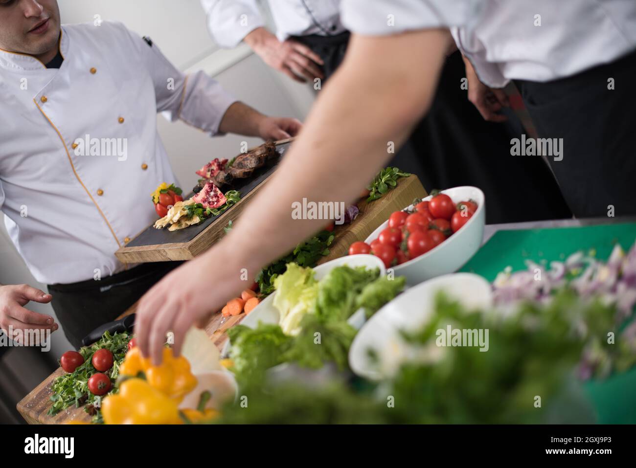 Professional team cooks and chefs preparing meal at busy hotel or ...