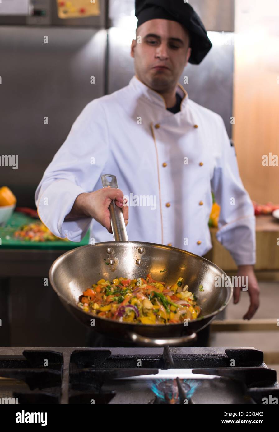 Young male chef flipping vegetables in wok at commercial kitchen Stock ...