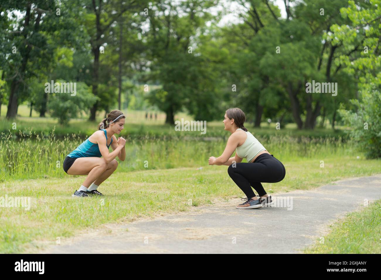 Two attractive and beautiful girls are doing squats Stock Photo - Alamy