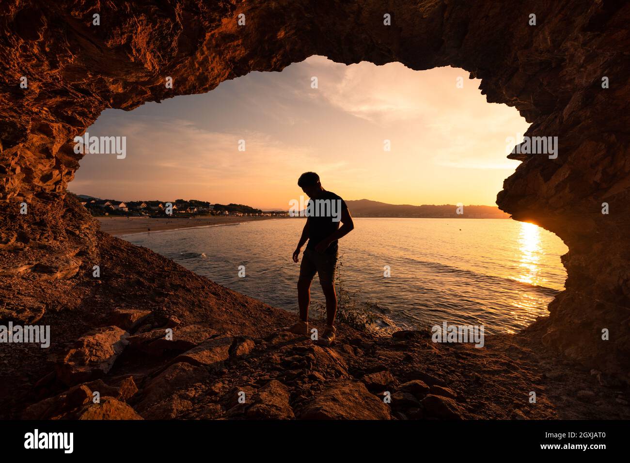 Young man silhouette in a coastal cave next to Hendaia beach, at the ...