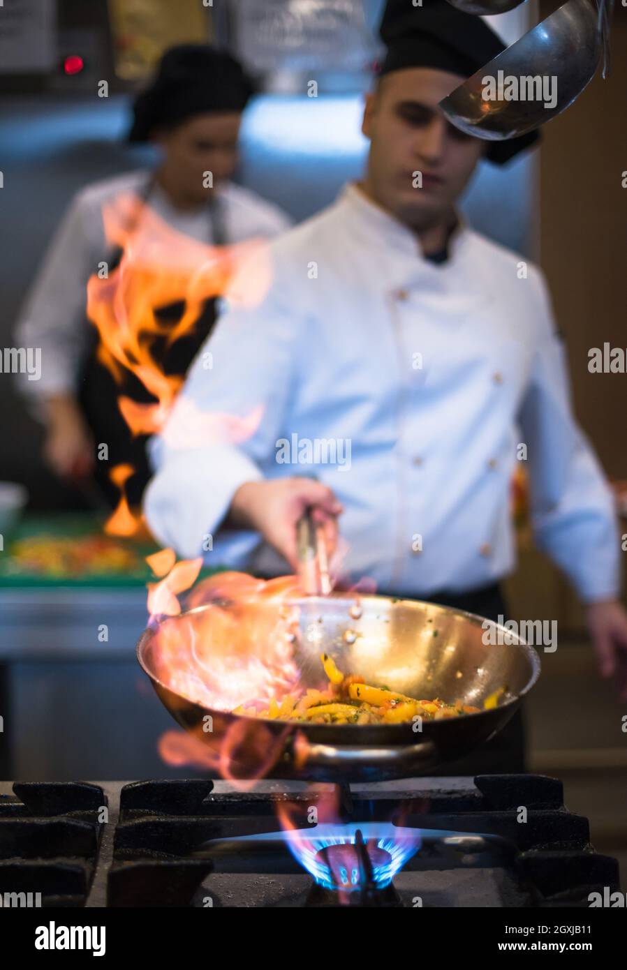 Chef cooking and doing flambe on food in restaurant kitchen Stock Photo ...