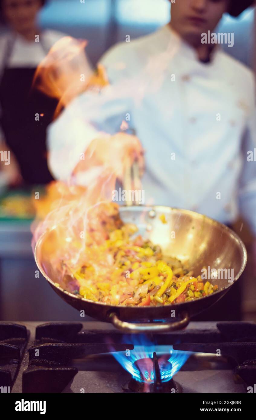 Chef cooking and doing flambe on food in restaurant kitchen Stock Photo ...