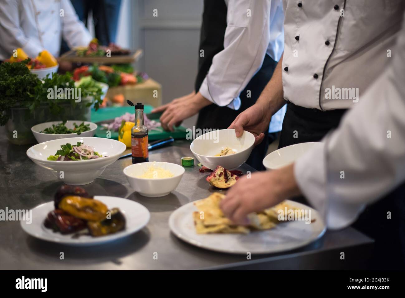Professional team cooks and chefs preparing meal at busy hotel or ...