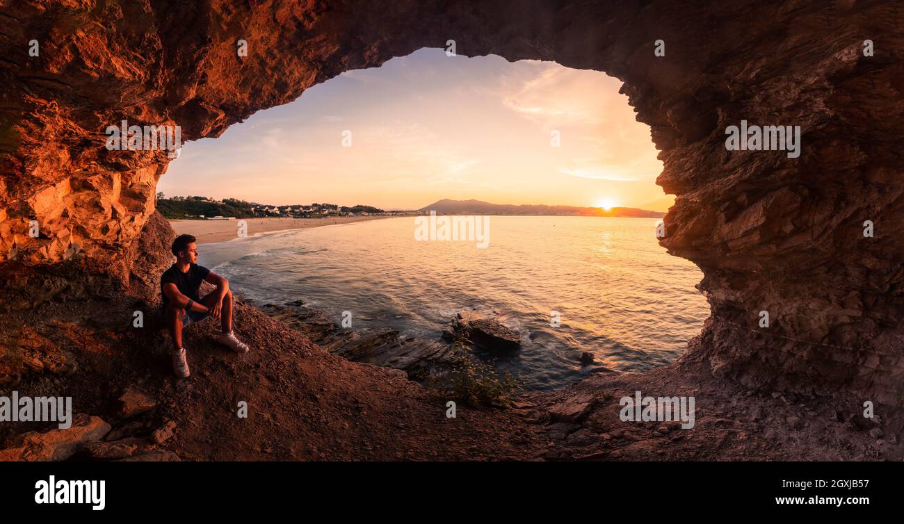 Young man silhouette in a coastal cave next to Hendaia beach, at the ...