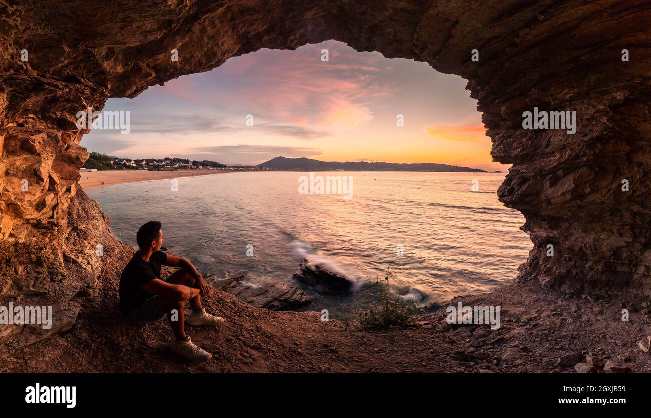 Young man silhouette in a coastal cave next to Hendaia beach, at the ...